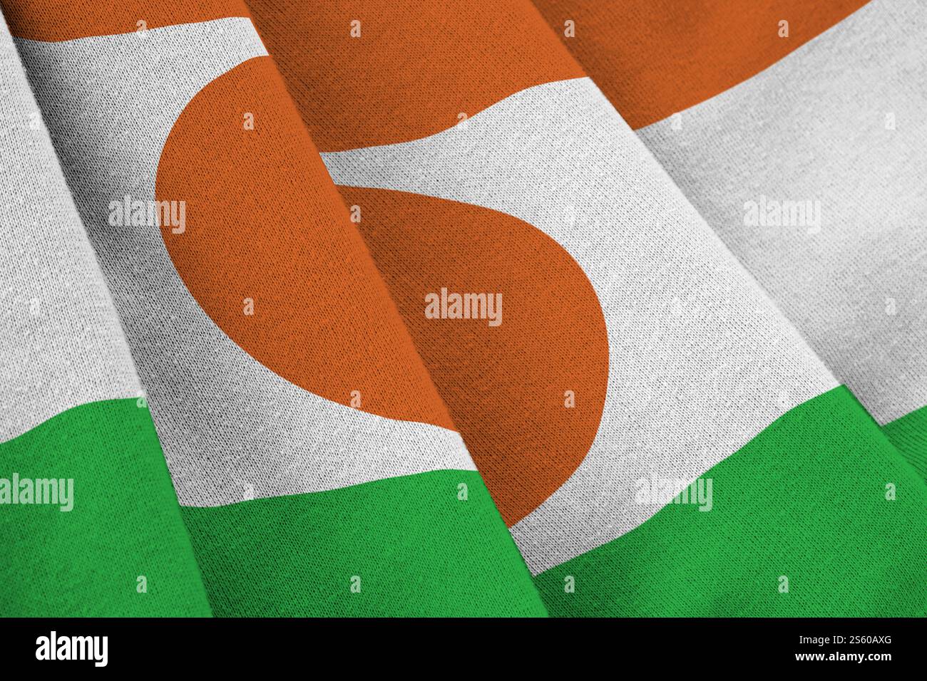 Niger flag with big folds waving close up under the studio light ...