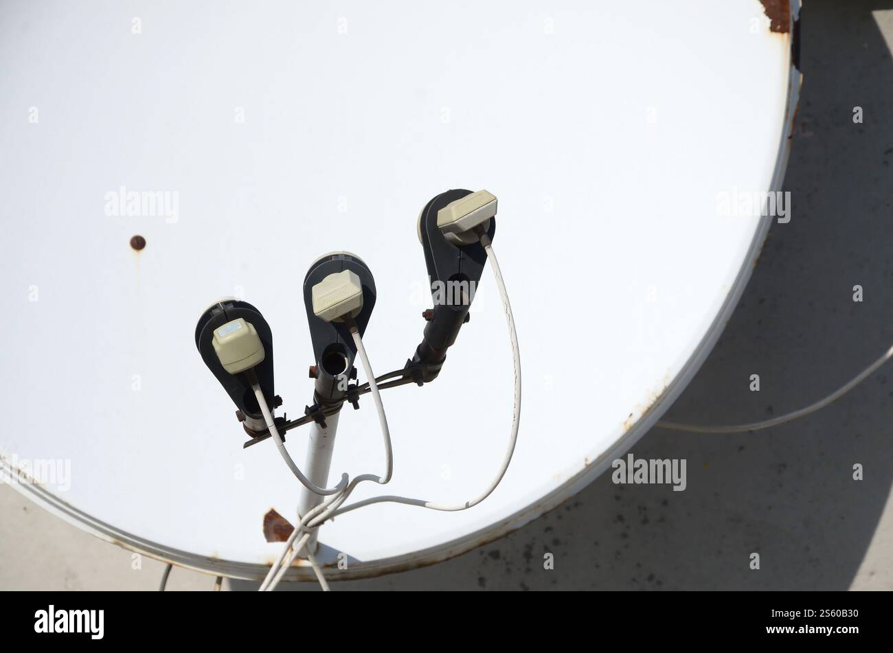 White satellite dish with three converters mounted on residental ...