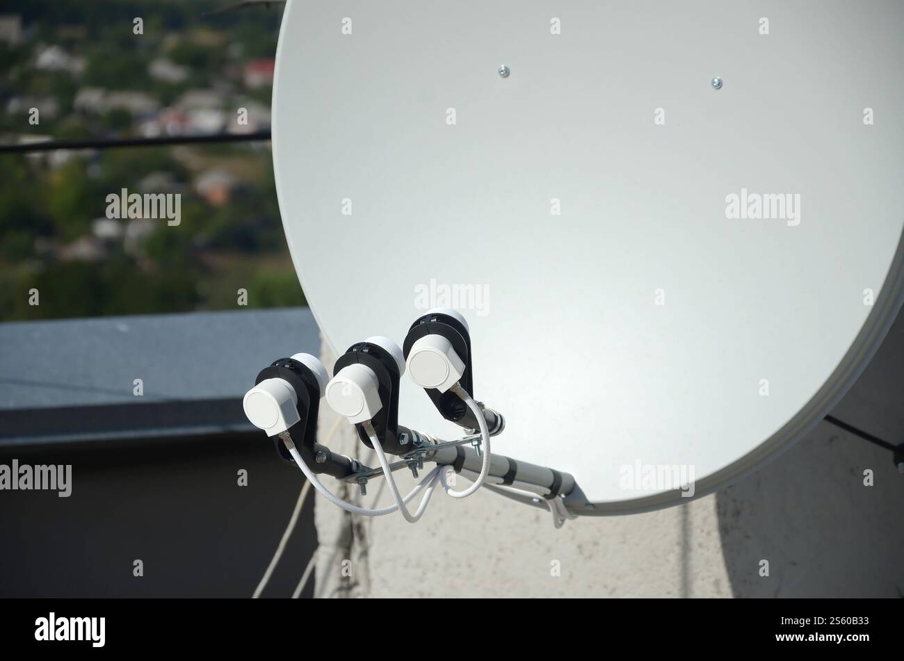 White satellite dish with three converters mounted on residental ...