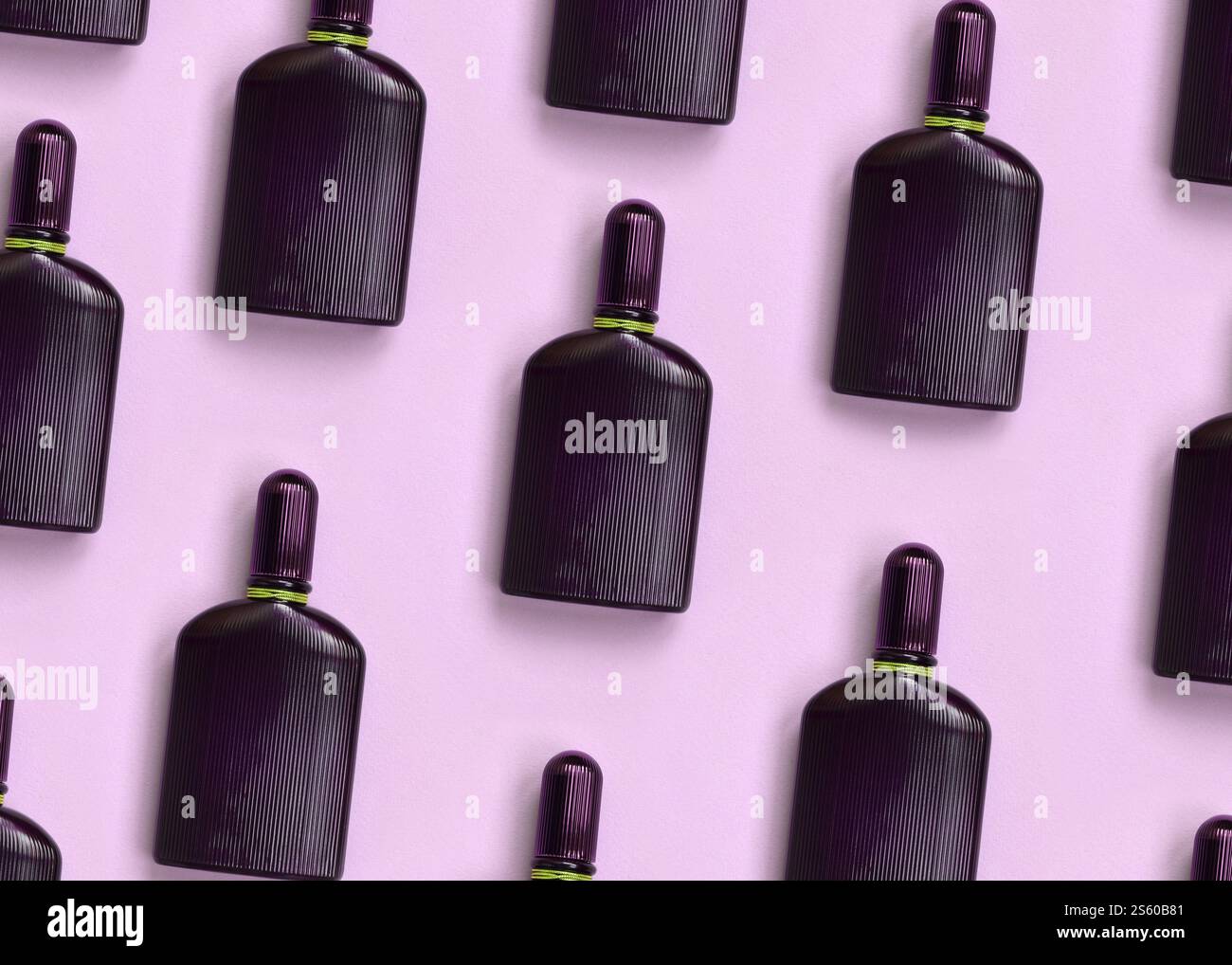 Dark purple perfume bottle with golden ribbon on pastel paper ...