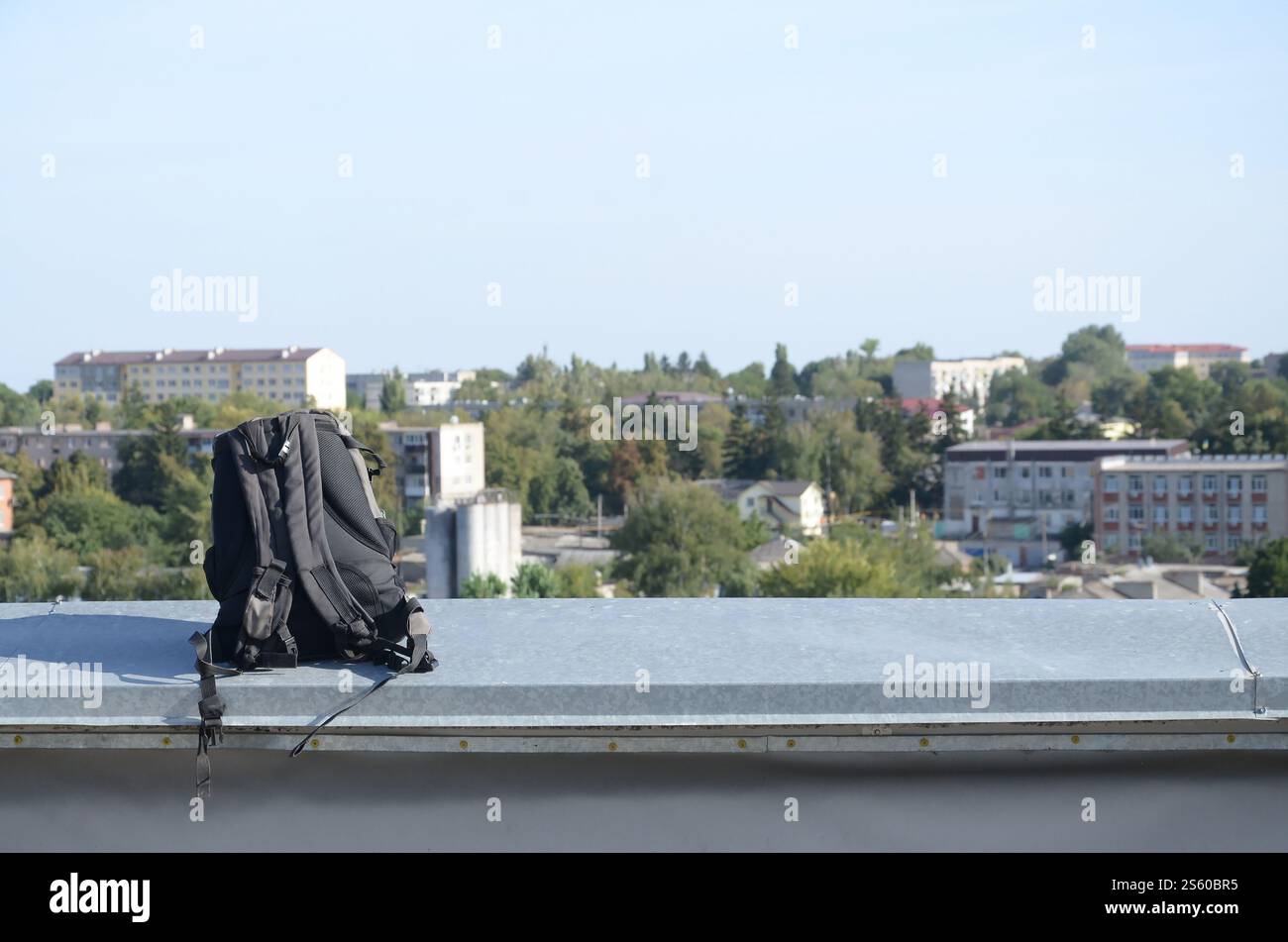 Black backpack lies on metal border of residental multistorey building ...