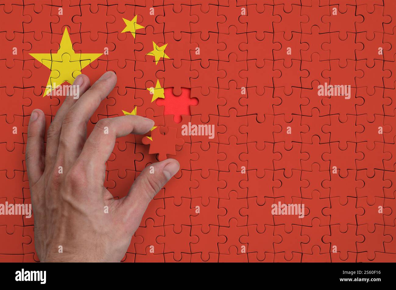 China flag is depicted on a puzzle, which the mans hand completes to ...
