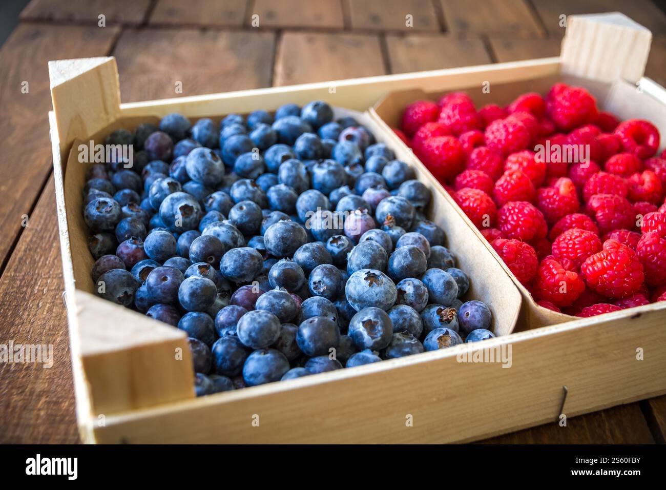 Wooden crate filled with fresh blueberries and raspberries. Wooden ...