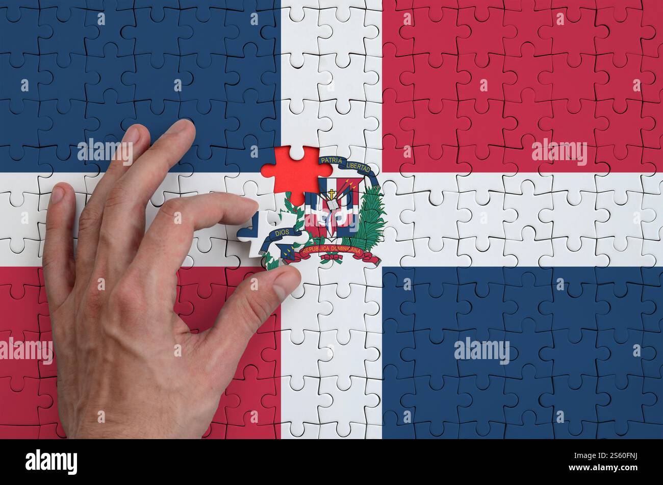 Dominican Republic flag is depicted on a puzzle, which the mans hand ...