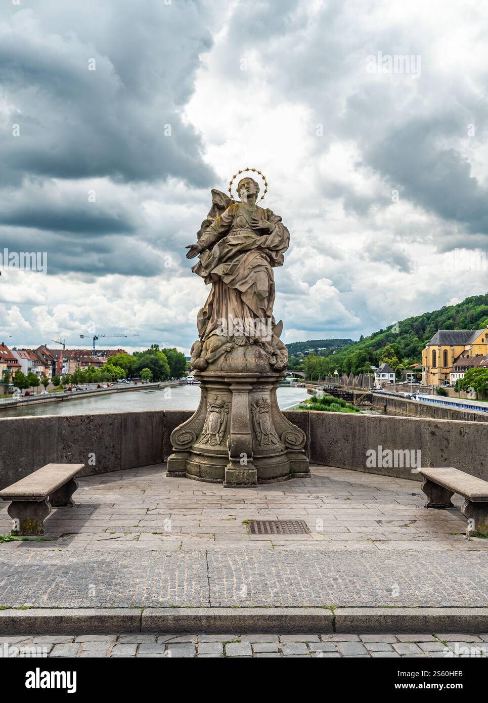 A detailed stone statue displayed on a historic bridge over a calm ...