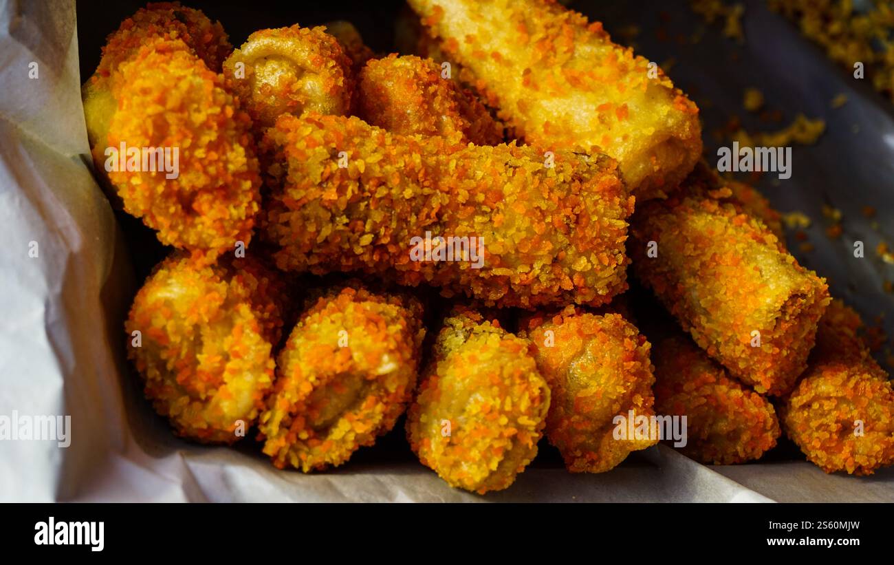 Close up of crispy fried snacks coated with orange and yellow ...