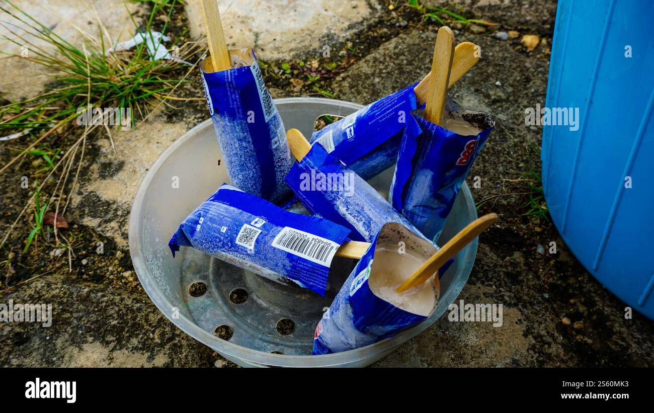 A bowl filled with empty ice cream wrappers and wooden sticks on a ...