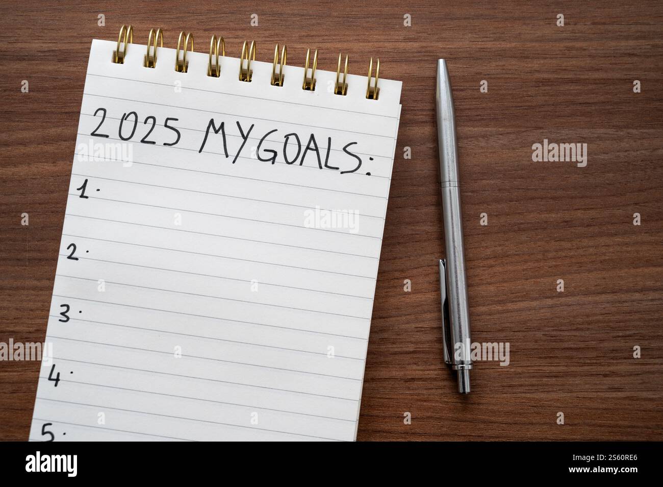 Notepad with text 2025 My Goals, on wooden surface. Priorities and ...
