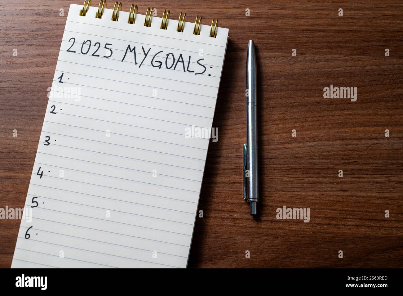 Notepad with text 2025 My Goals, on wooden surface. Priorities and ...
