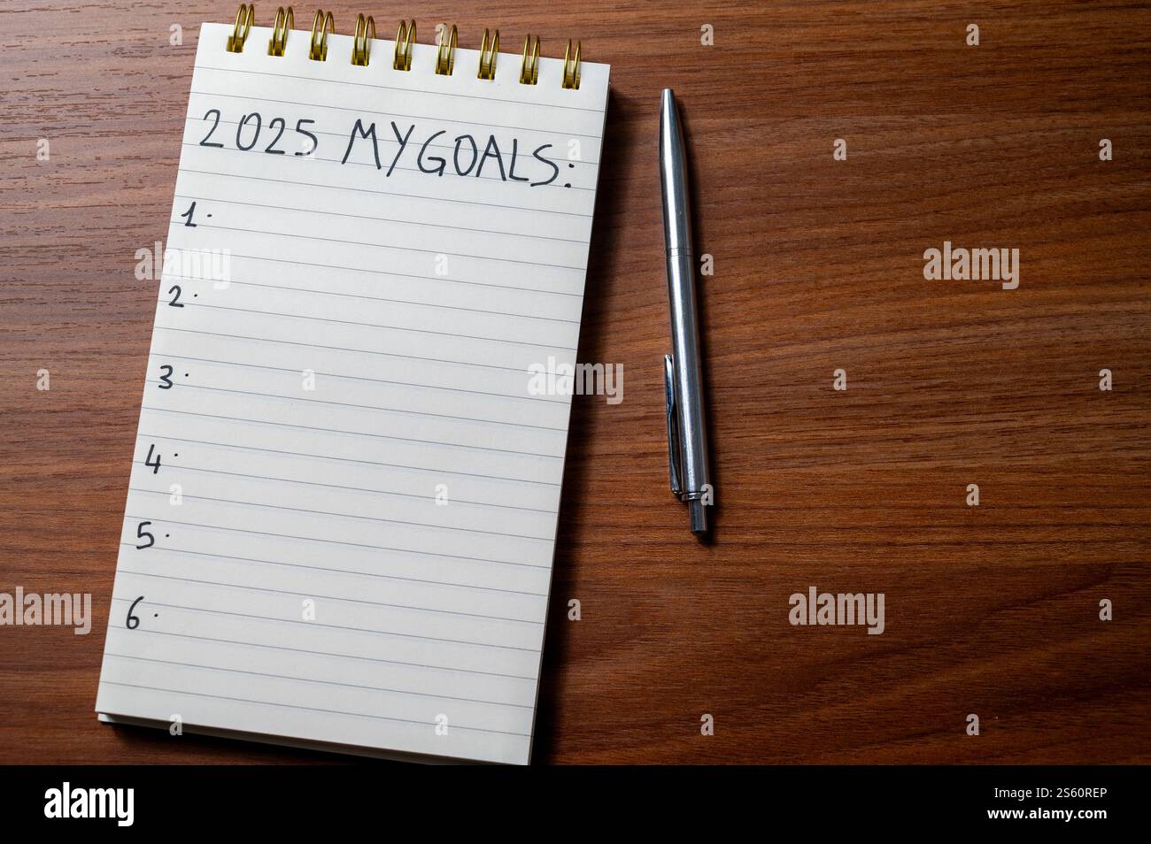 Notepad with text 2025 My Goals, on wooden surface. Priorities and ...