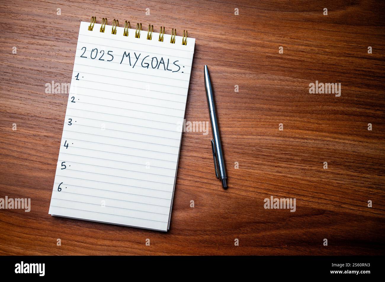 Notepad with text 2025 My Goals, on wooden surface. Priorities and ...