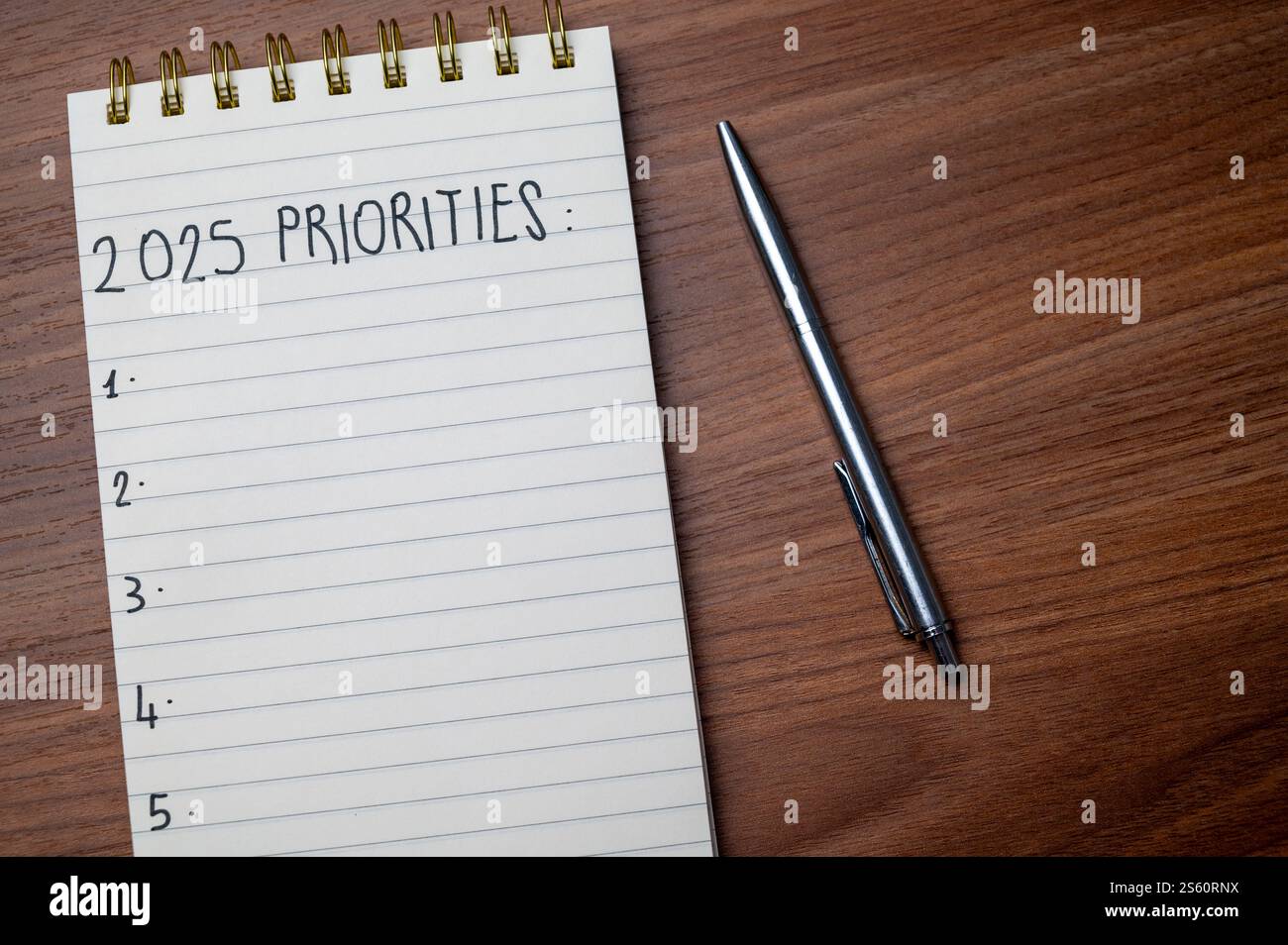 Notepad with text 2025 Priorities, on wooden surface. Priorities and ...