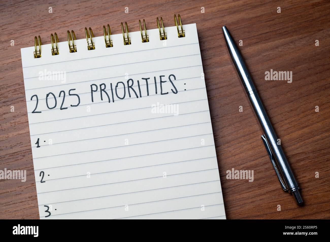 Notepad with text 2025 Priorities, on wooden surface. Priorities and ...