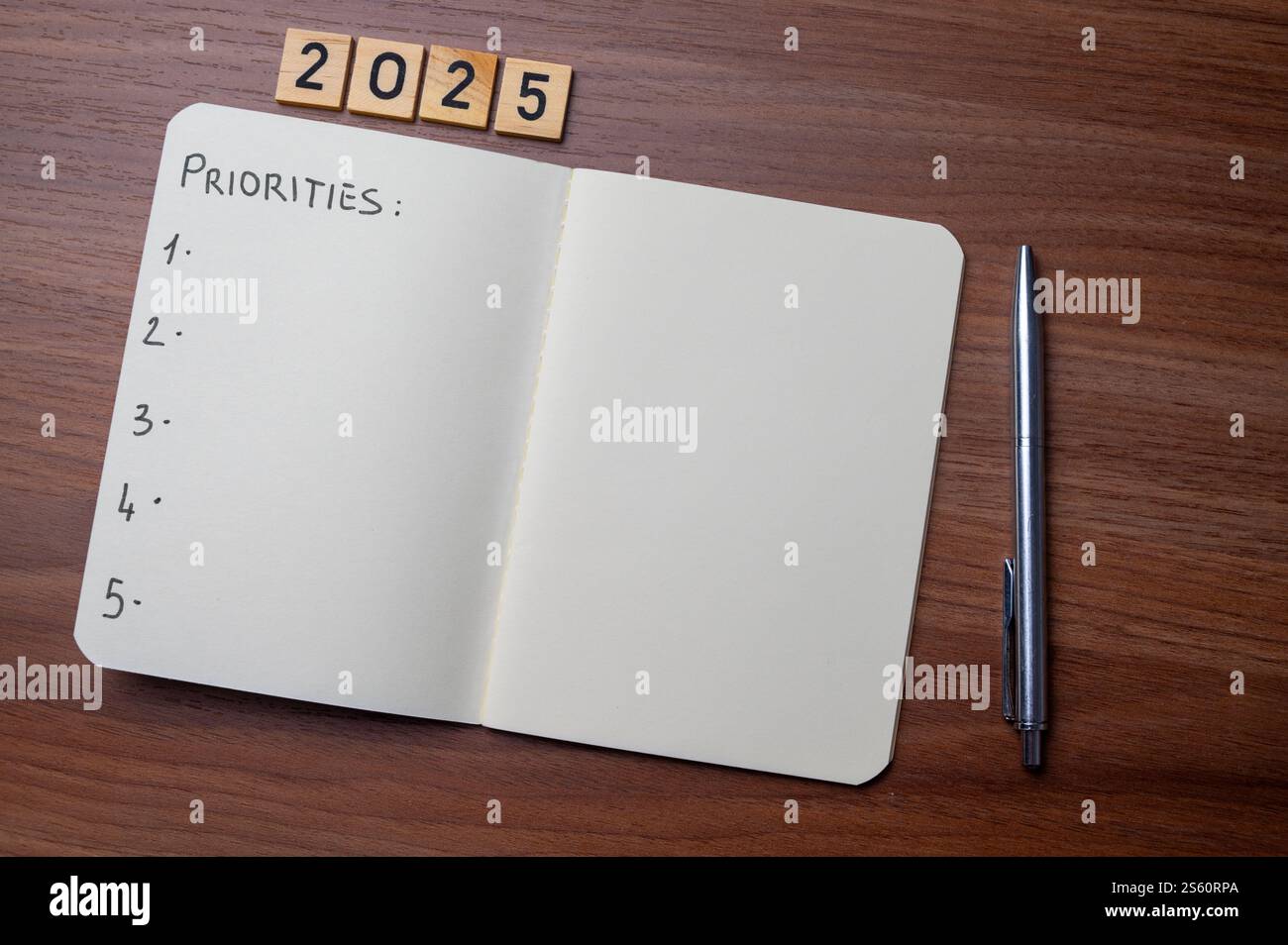 Notepad with text 2025 Priorities, on wooden surface. Priorities and ...