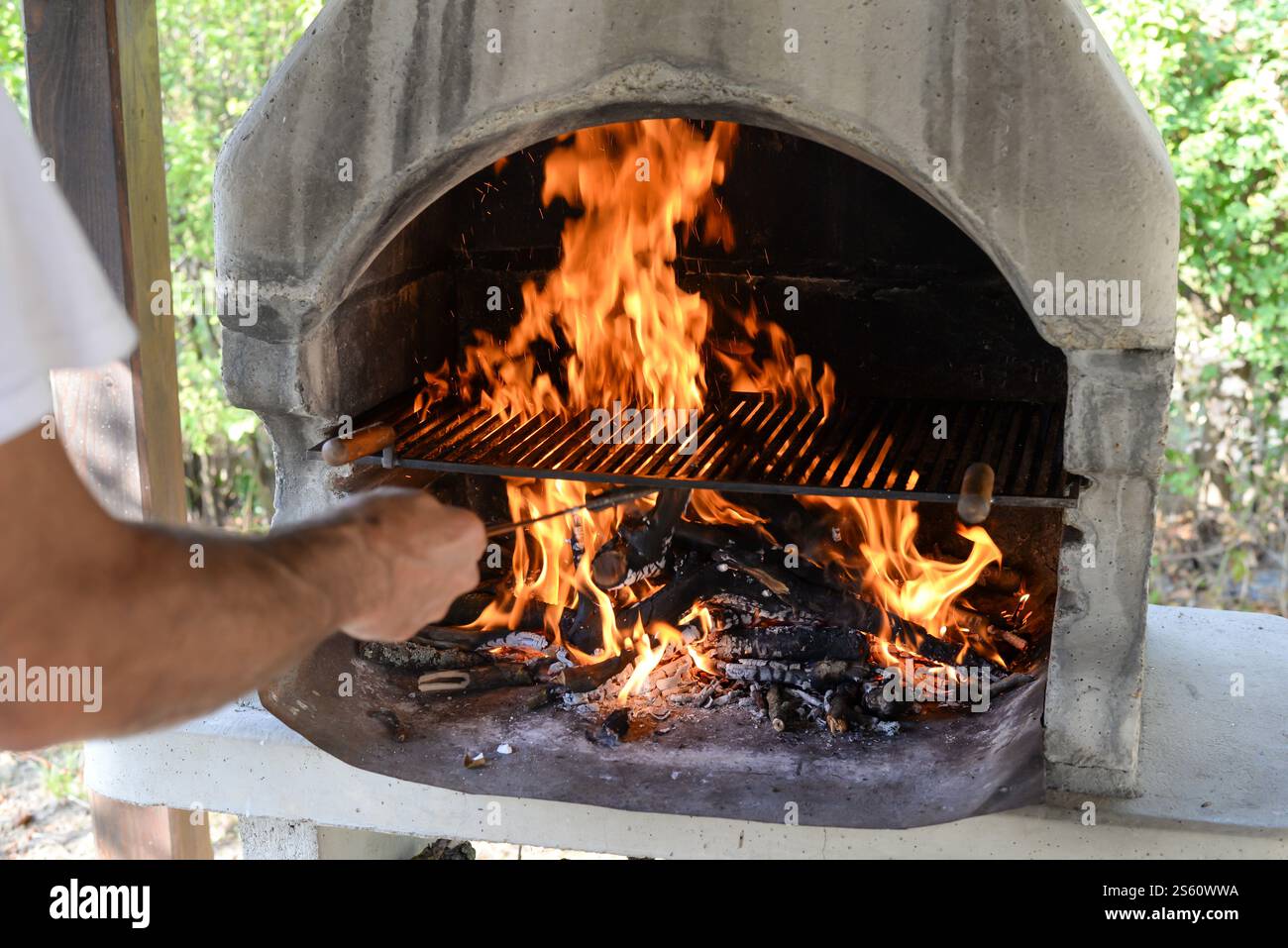 Hand keeps fire going in a grill with fiery flames - an empty fire ...