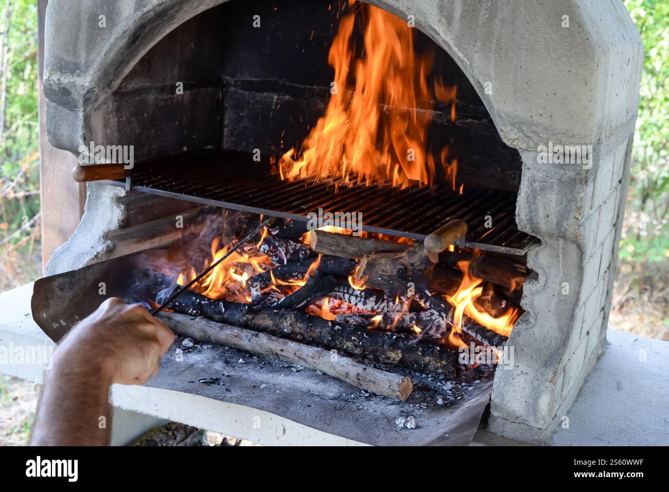 Hand keeps fire going in a grill with fiery flames - an empty fire ...