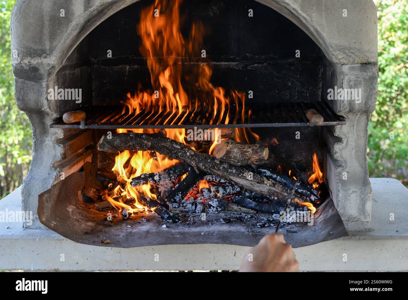 Hand keeps fire going in a grill with fiery flames - an empty fire ...
