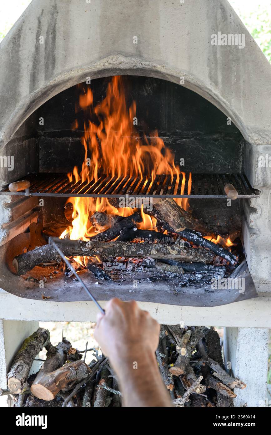 Hand keeps fire going in a grill with fiery flames - an empty fire ...
