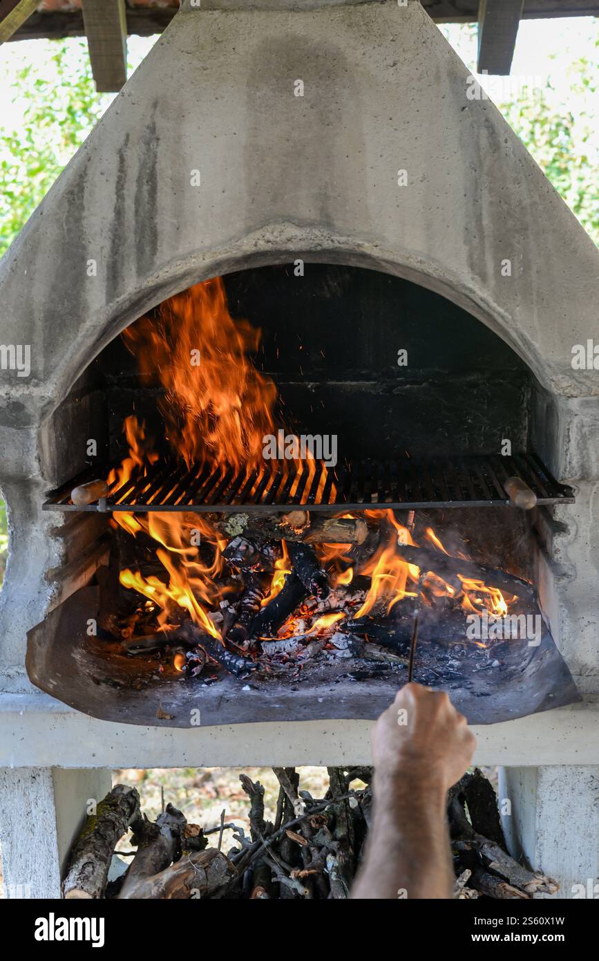 Hand keeps fire going in a grill with fiery flames - an empty fire ...