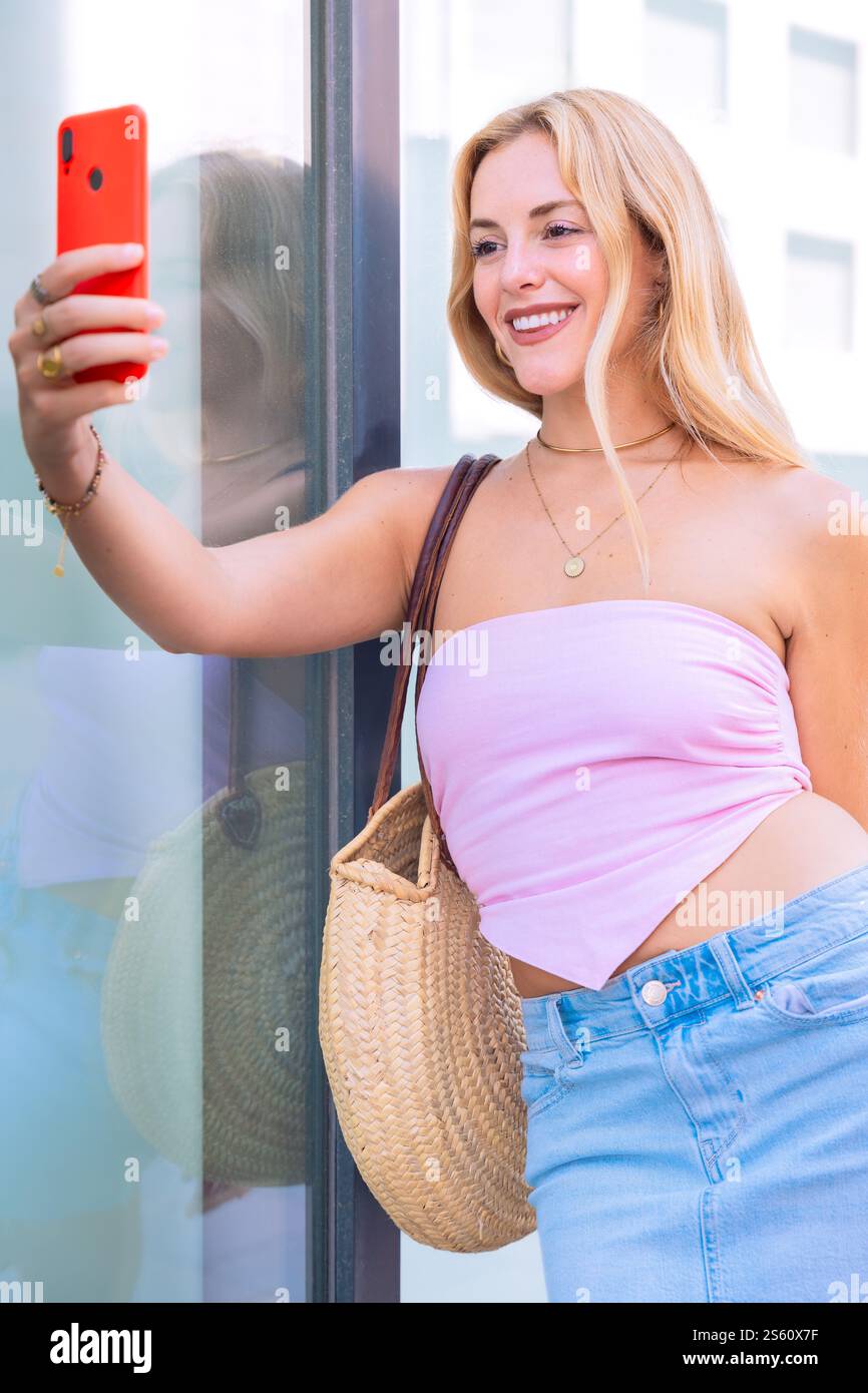 Smiling Blonde Woman Taking a Selfie Outdoors with a Smartphone ...