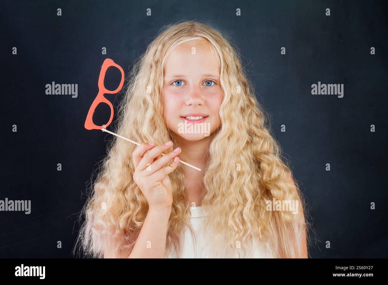 Portrait of cheerful young girl posing with photo booth props glasses ...