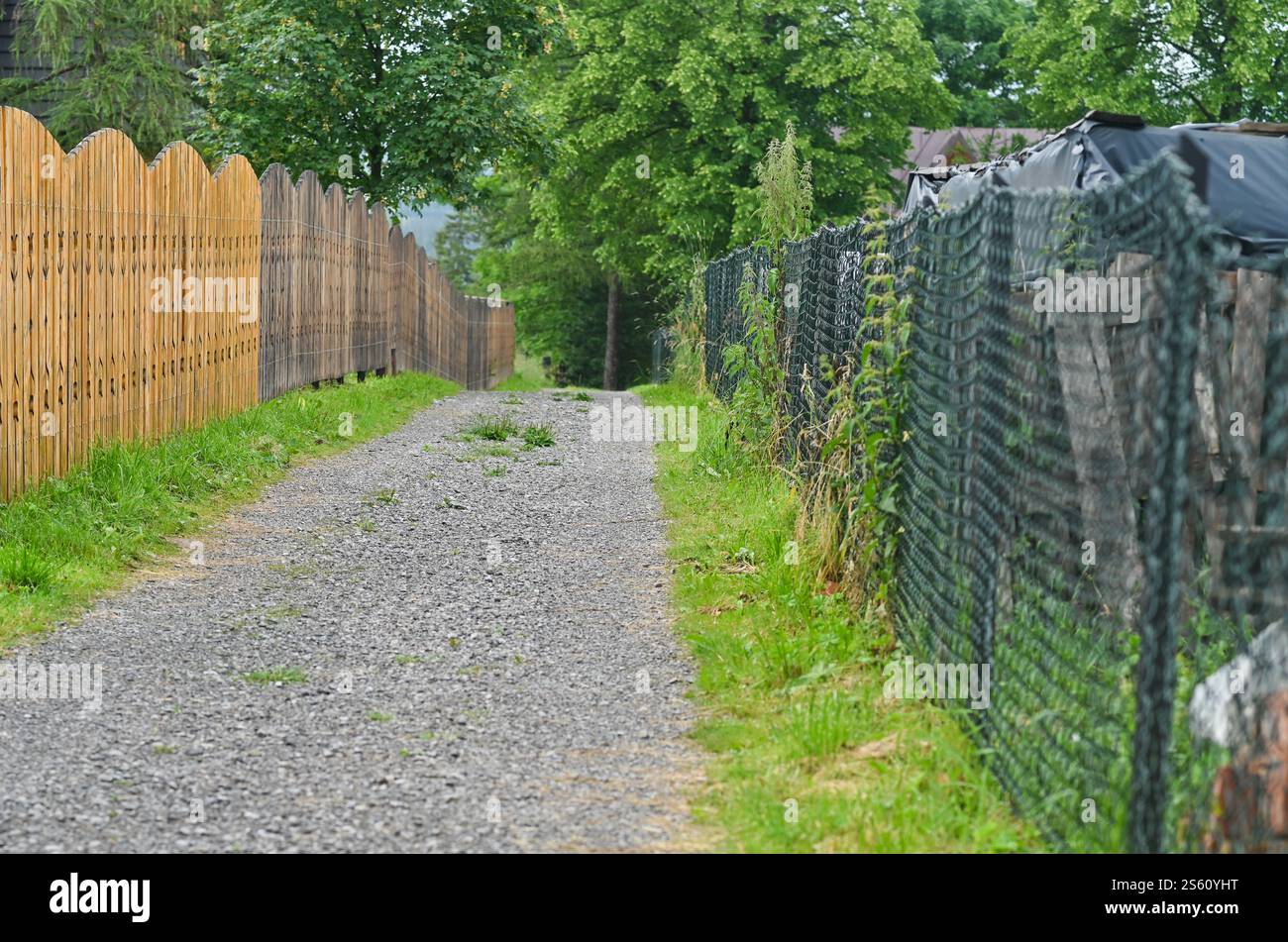 Crushed stone road. a passage between two fences. wooden and metal ...