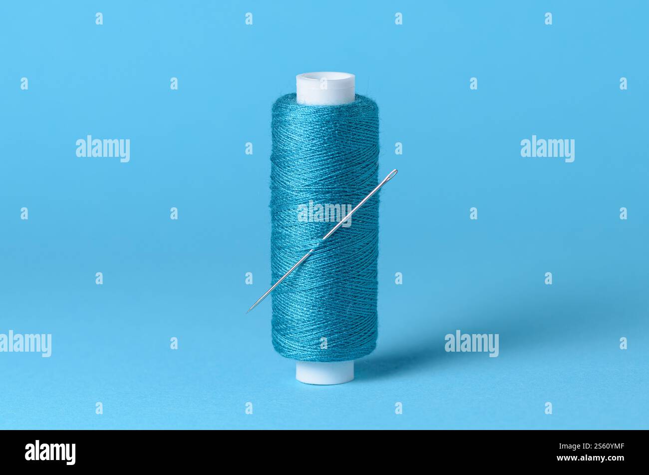 One single blue thread spool with needle close-up flat lay top view ...