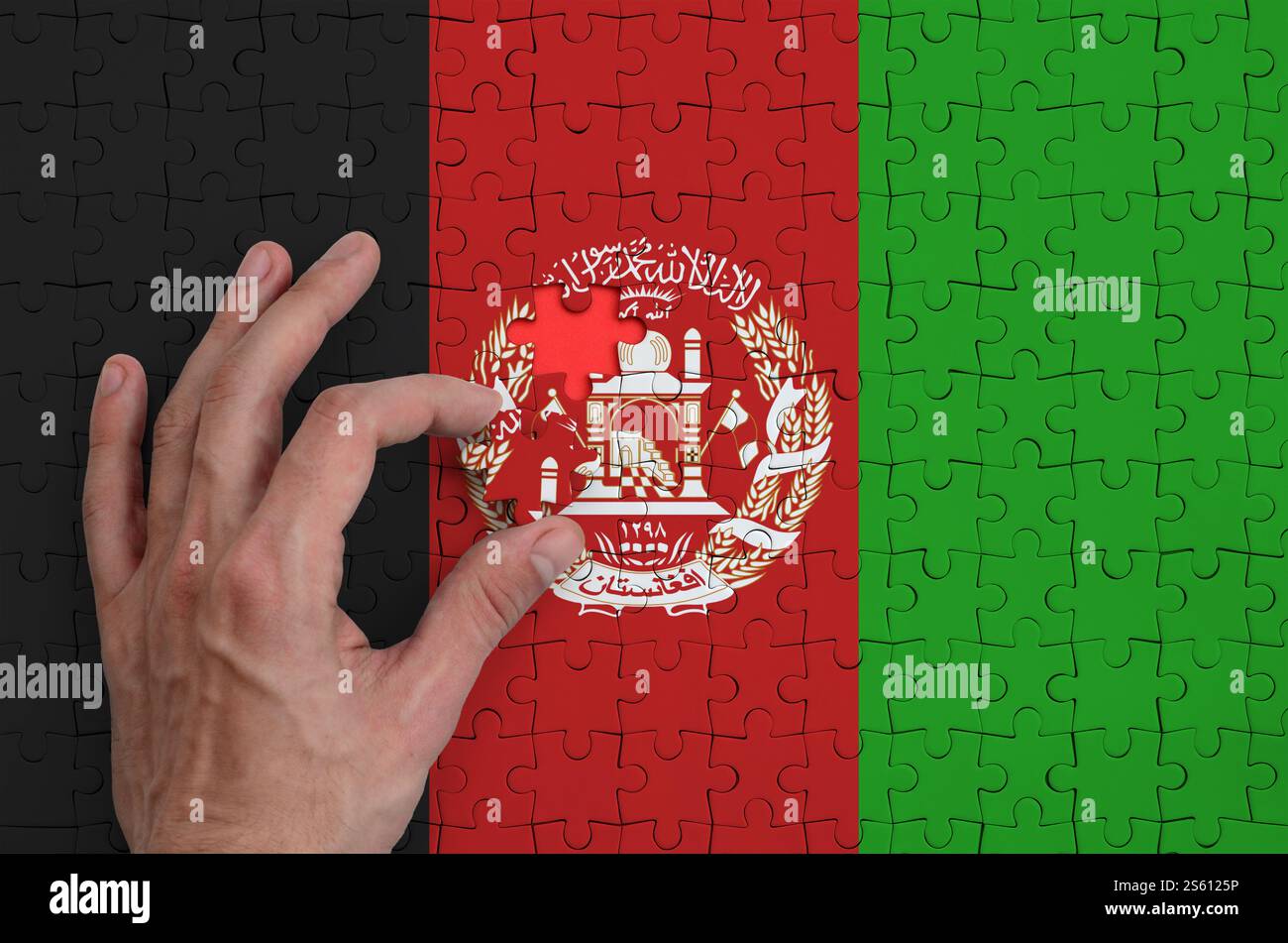 Afghanistan flag is depicted on a puzzle, which the mans hand completes ...