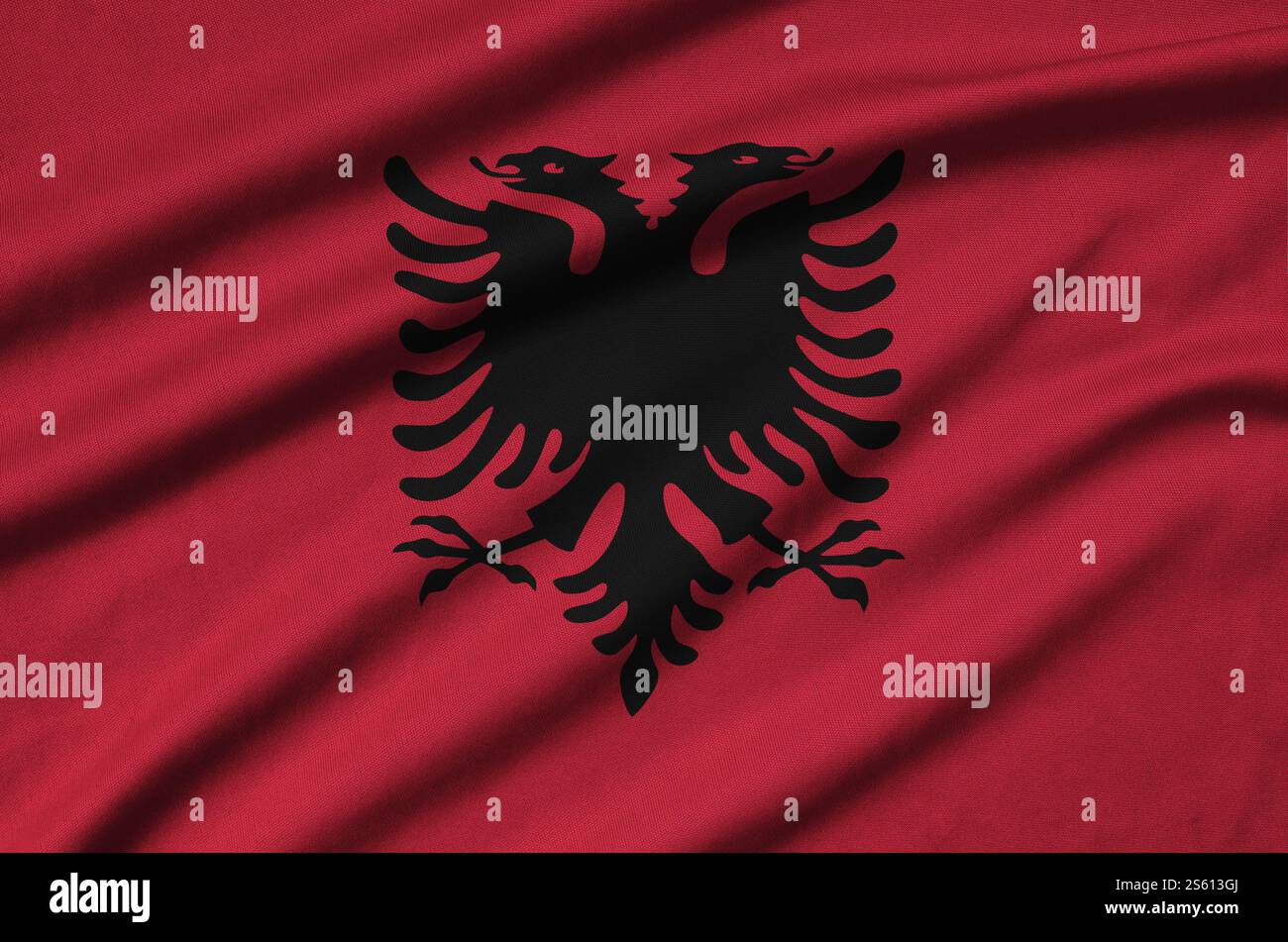 Albania flag is depicted on a sports cloth fabric with many folds ...