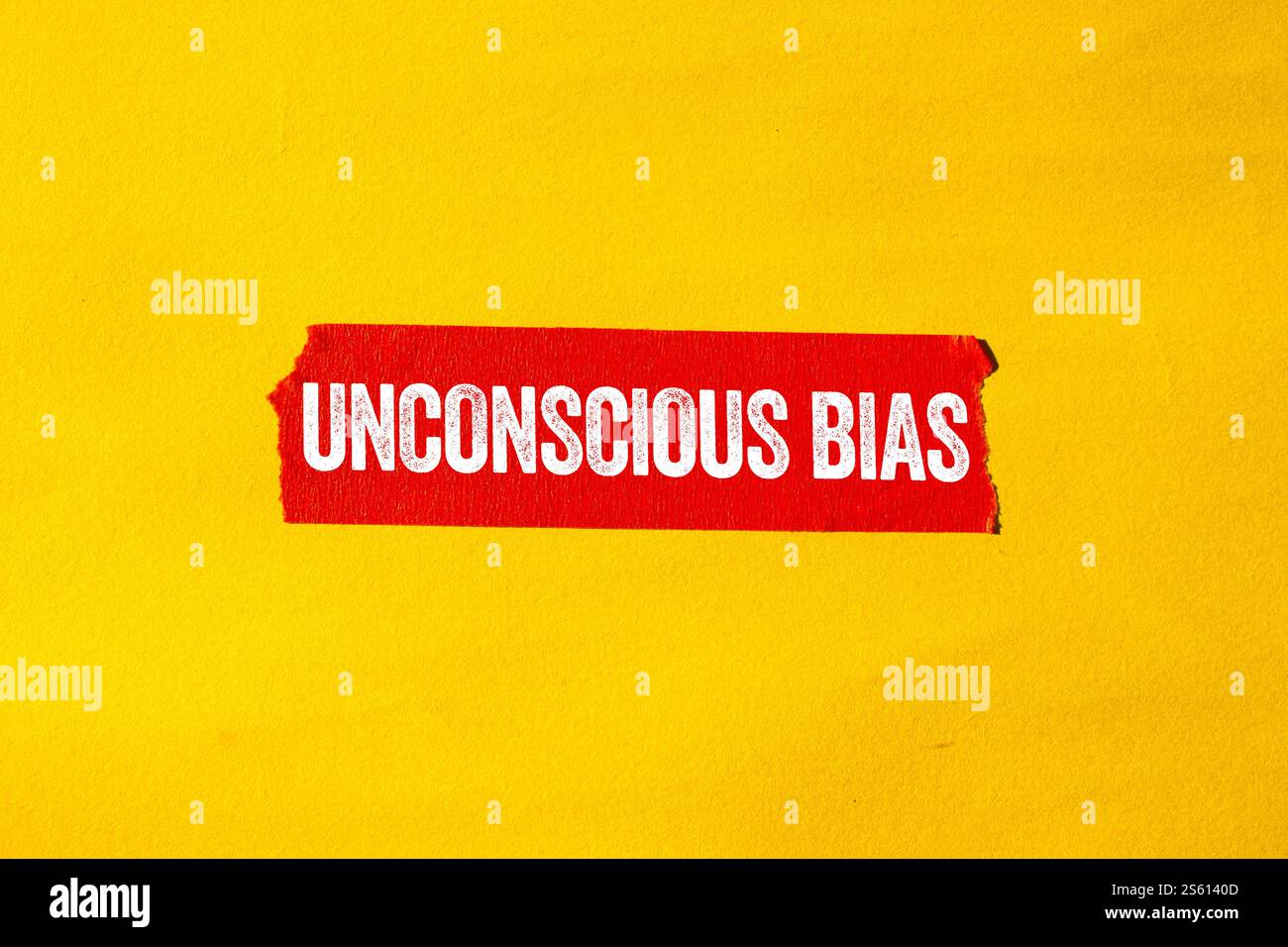 Unconscious bias message written on ripped torn red paper tape on yellow background. Conceptual ...