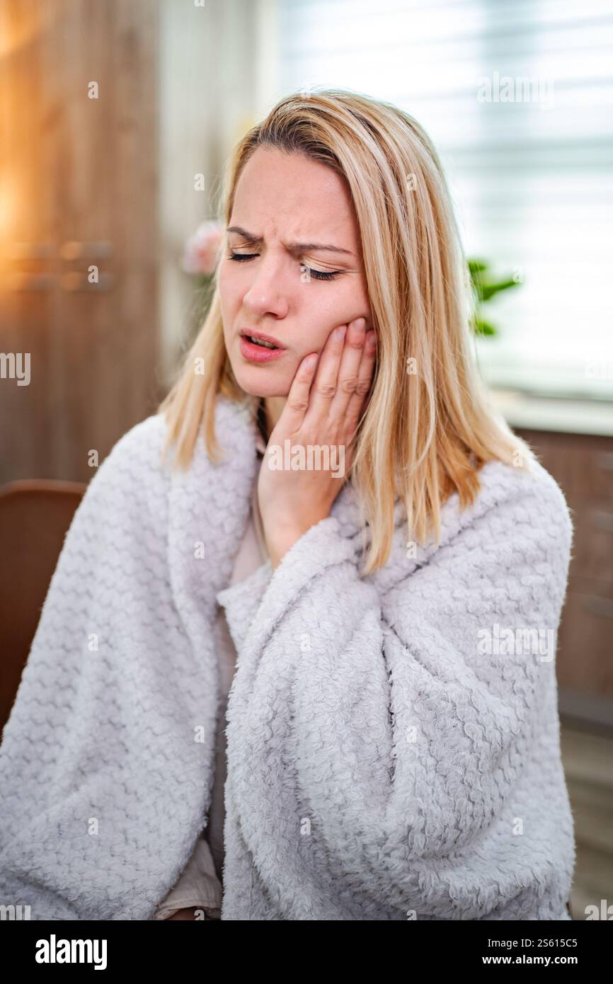 Young woman shows signs of distress, cradling her face in a warm space ...