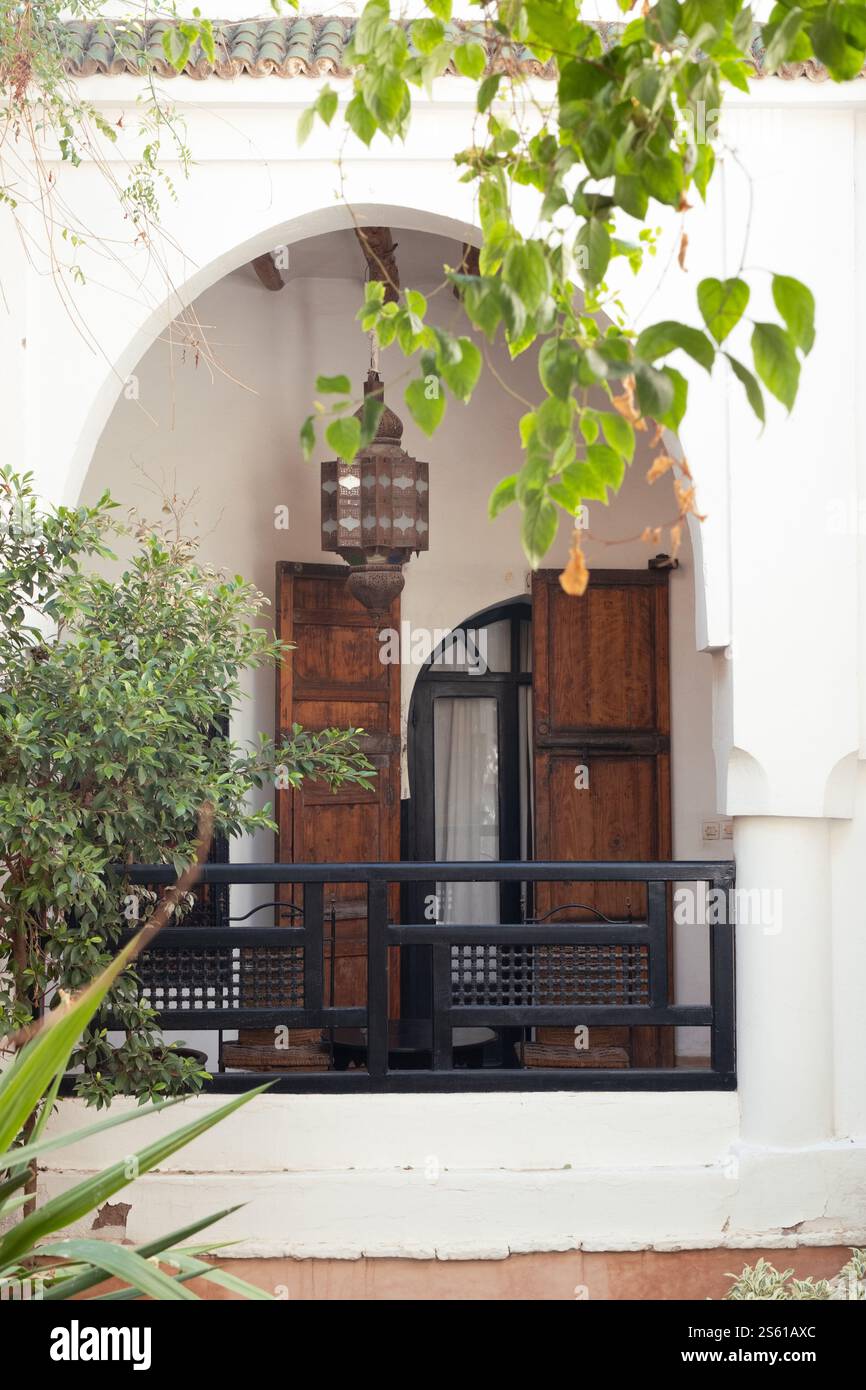 Moorish arch of a balcony with brown wooden doors and an overhead lamp ...