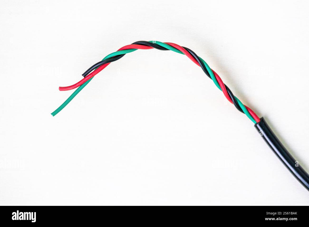 Green, red, and black twisted wires from a cut cable on a white ...
