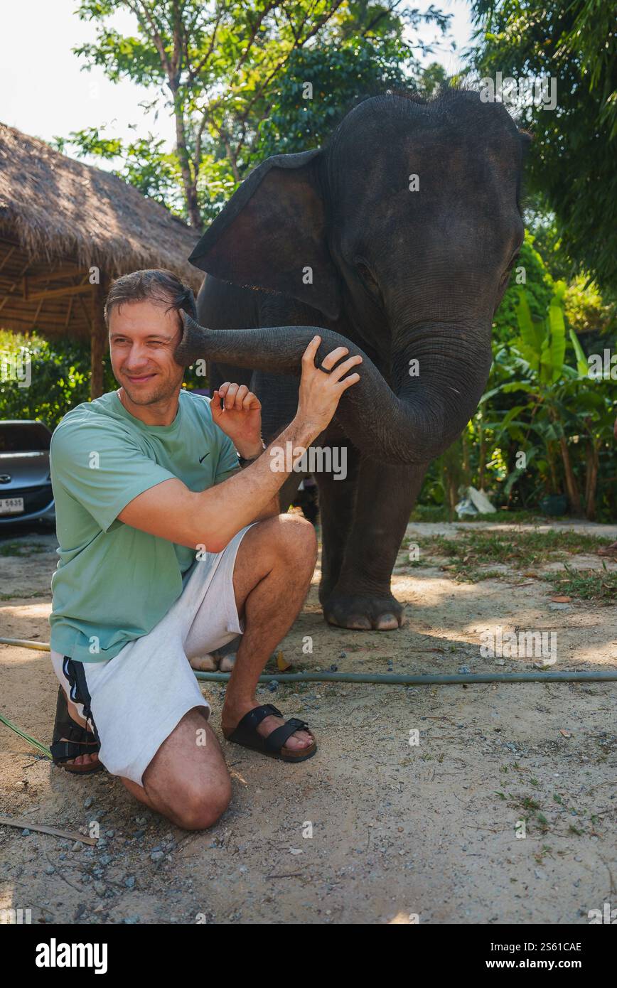Man Kneeling with Young Elephant in Tropical Setting, Thailand Stock ...