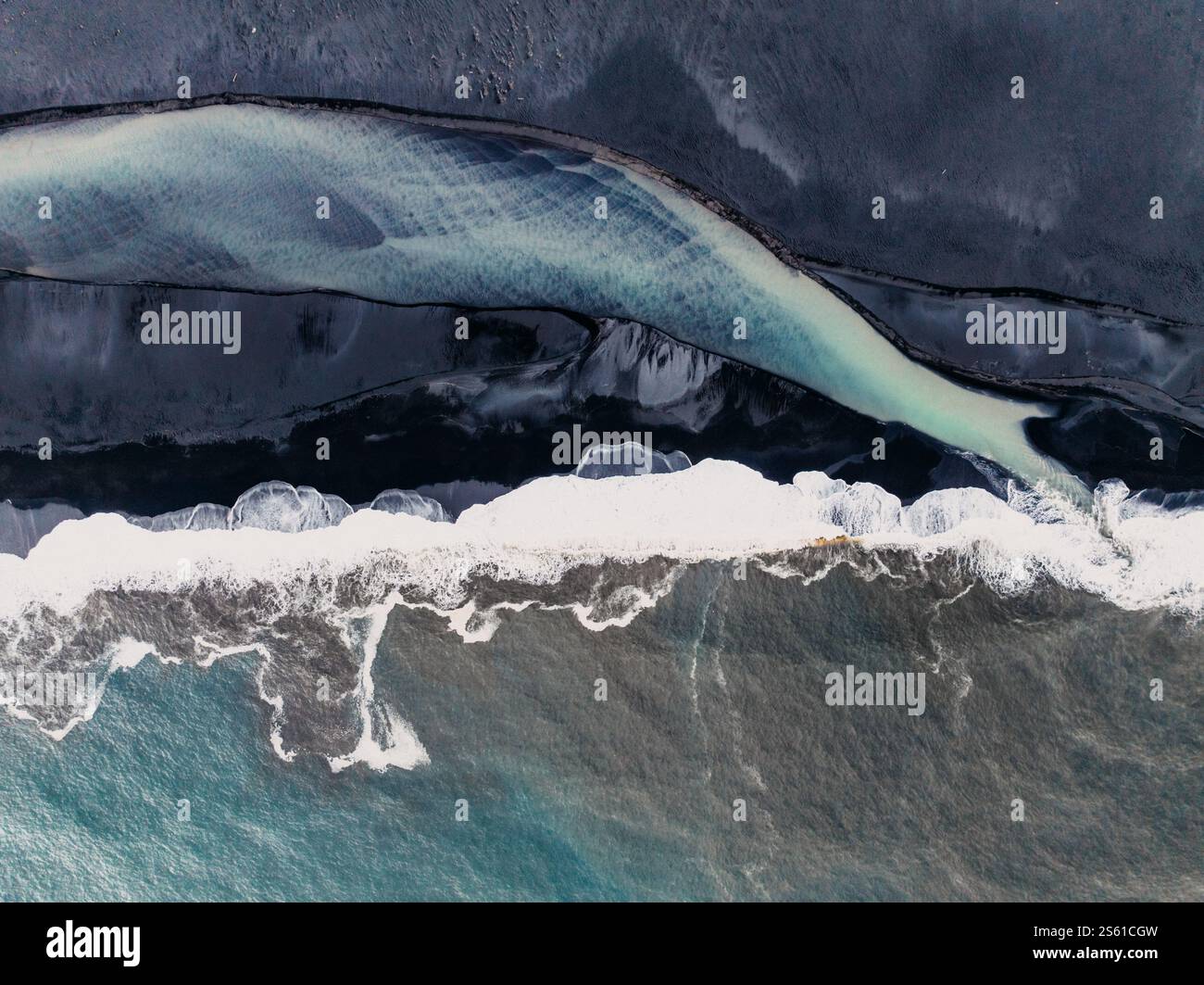 Aerial view of a glacial river merging with the ocean on a black sand ...