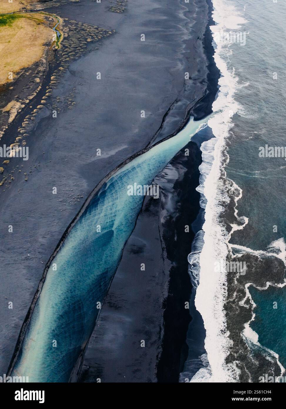 Aerial view of a glacial river merging with the ocean on a black sand ...