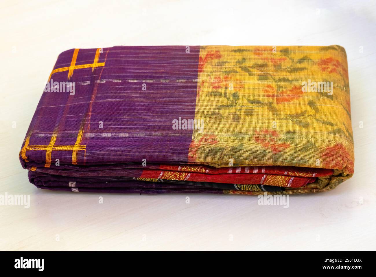 A folded cotton saree is showcased against a light wooden backdrop. In ...