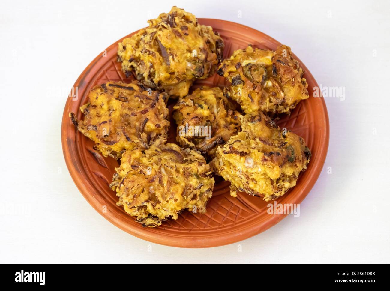 Crispy pakora on a clay plate, isolated on a white background. These ...