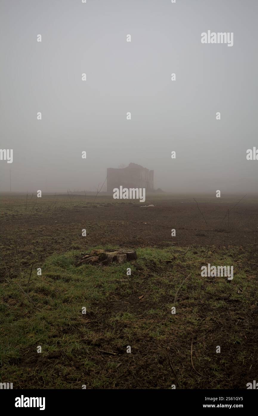 Run down country house in the middle of a field on a foggy day in the ...