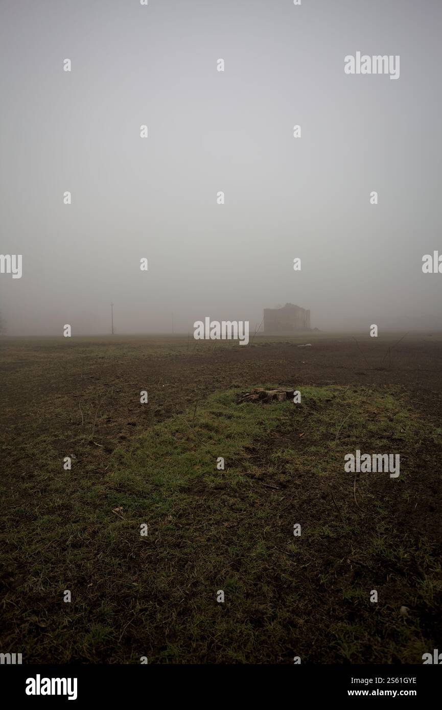 Run down country house in the middle of a field on a foggy day in the ...