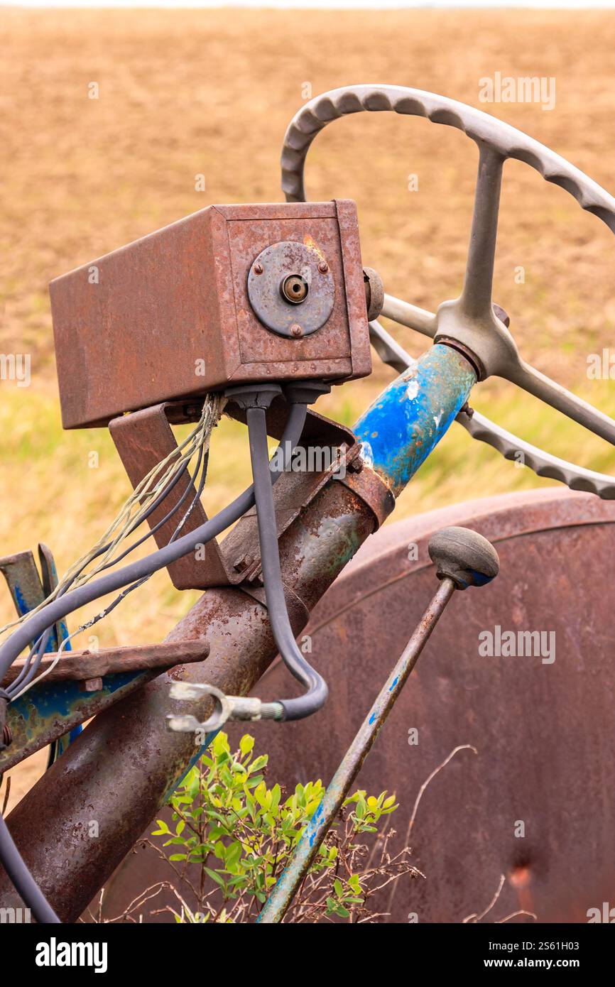 A rusty old tractor with a blue steering wheel. The steering wheel is ...