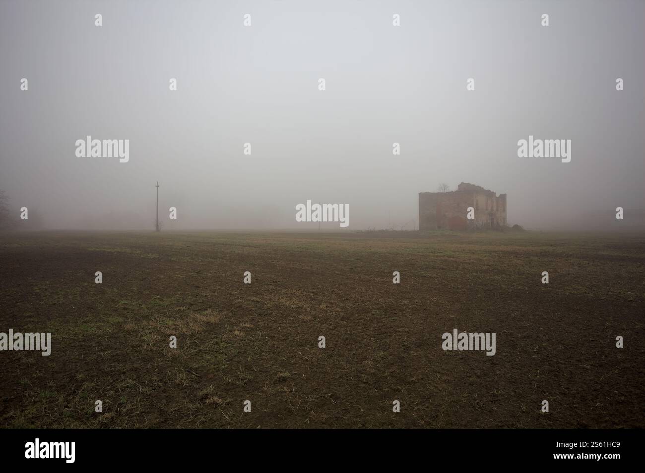 Run down country house in the middle of a field on a foggy day in the ...