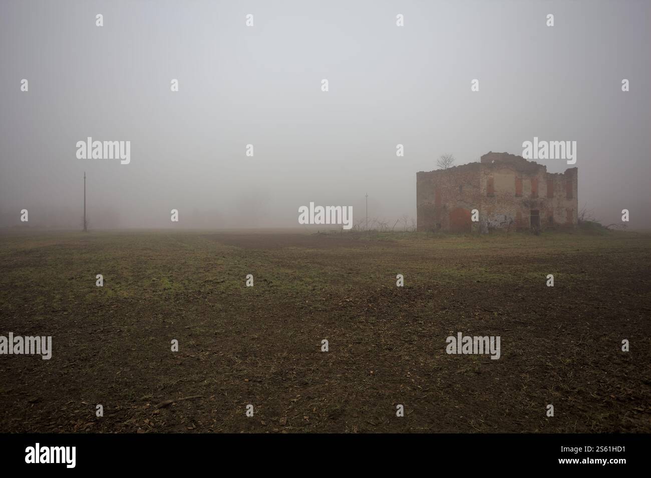 Run down country house in the middle of a field on a foggy day in the ...