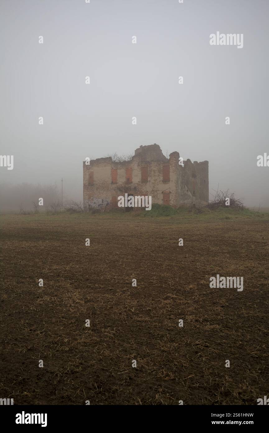 Run down country house in the middle of a field on a foggy day in the ...