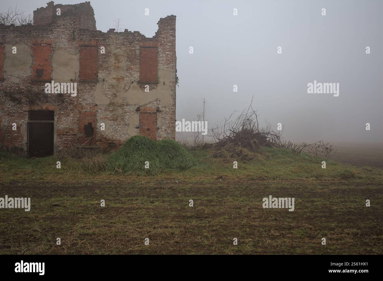 Run down country house in the middle of a field on a foggy day in the ...