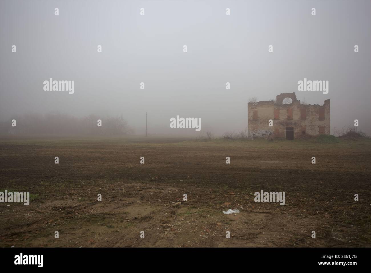 Run down country house in the middle of a field on a foggy day in the ...