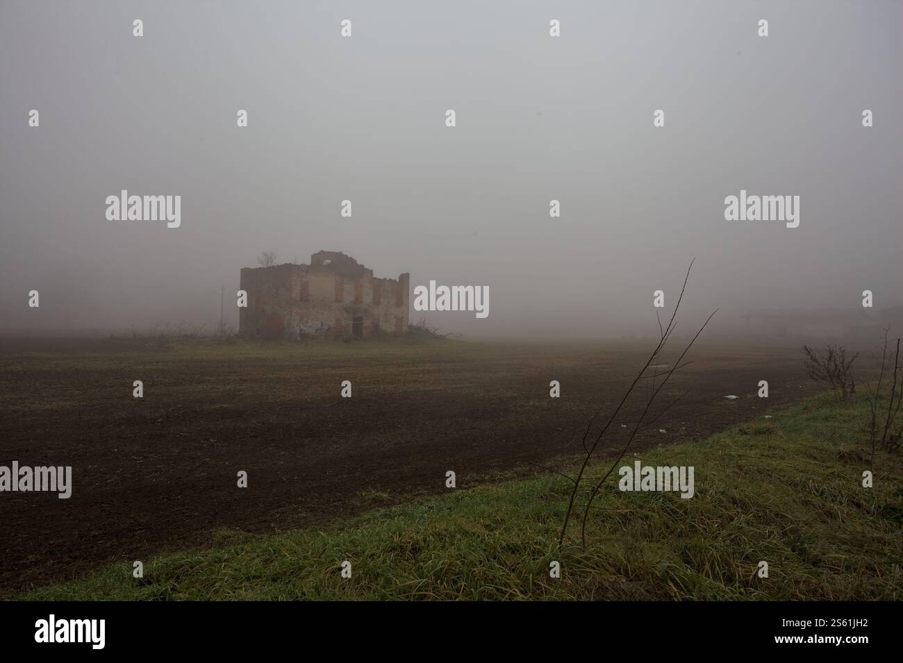 Run down country house in the middle of a field on a foggy day in the ...