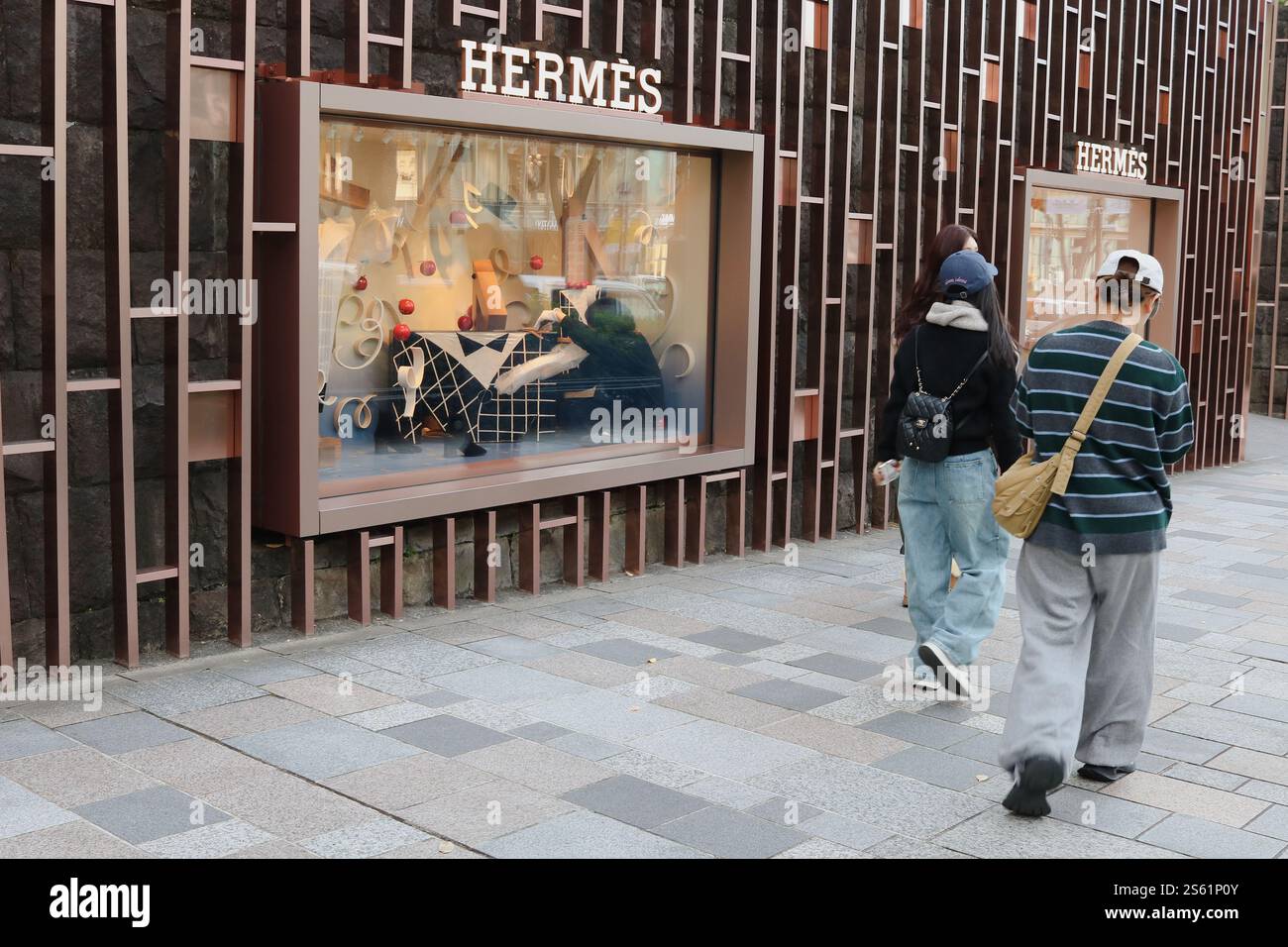 TOKYO, JAPAN - December 5, 2024: People pass the front of a Hermes ...