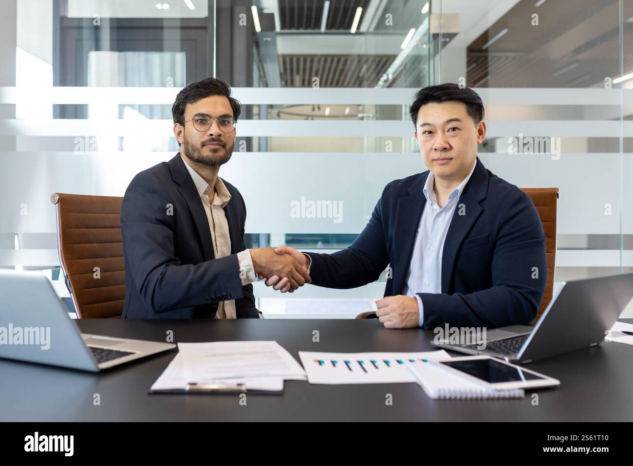 Two serious colleagues shaking hands. Serious and confident men in ...
