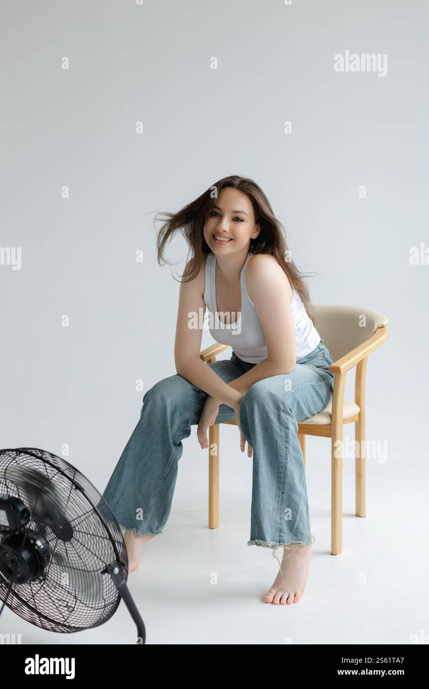 Young woman sitting comfortably on a chair, enjoying a refreshing ...